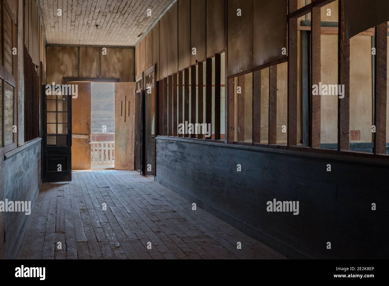 An empty hallway in a wooden building. The door at the end is open to ...