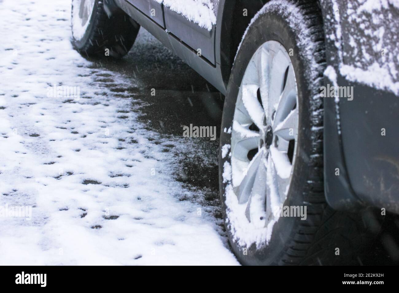 A new car wheel with a rubber tire closeup covered with white snow in a ...