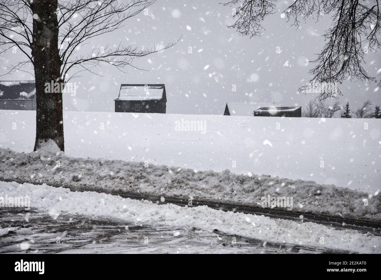 Beautiful shot of a snowy sidewalk with snow-covered roofs of houses ...