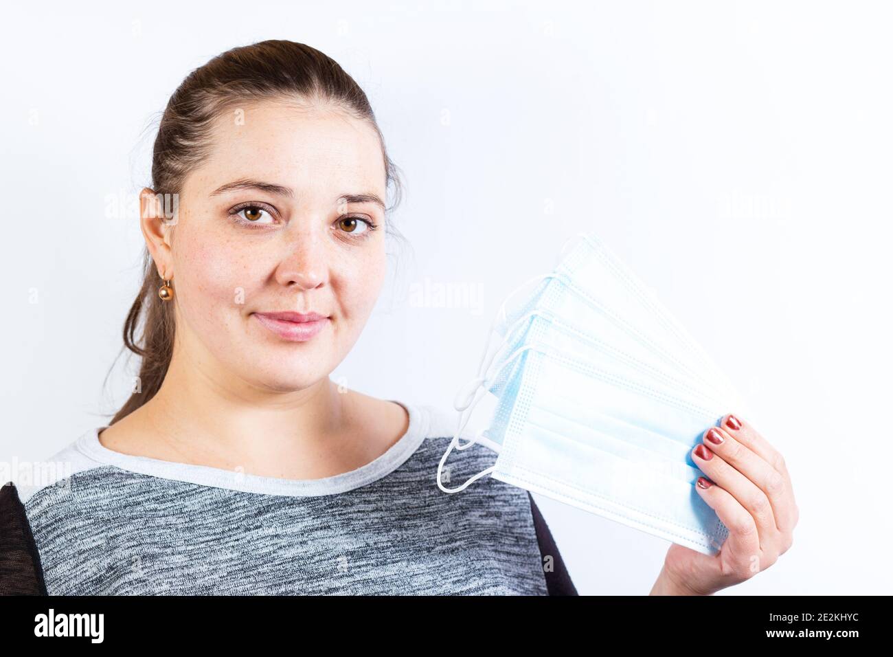 Young smiling woman holding medical masks on a white background Stock ...