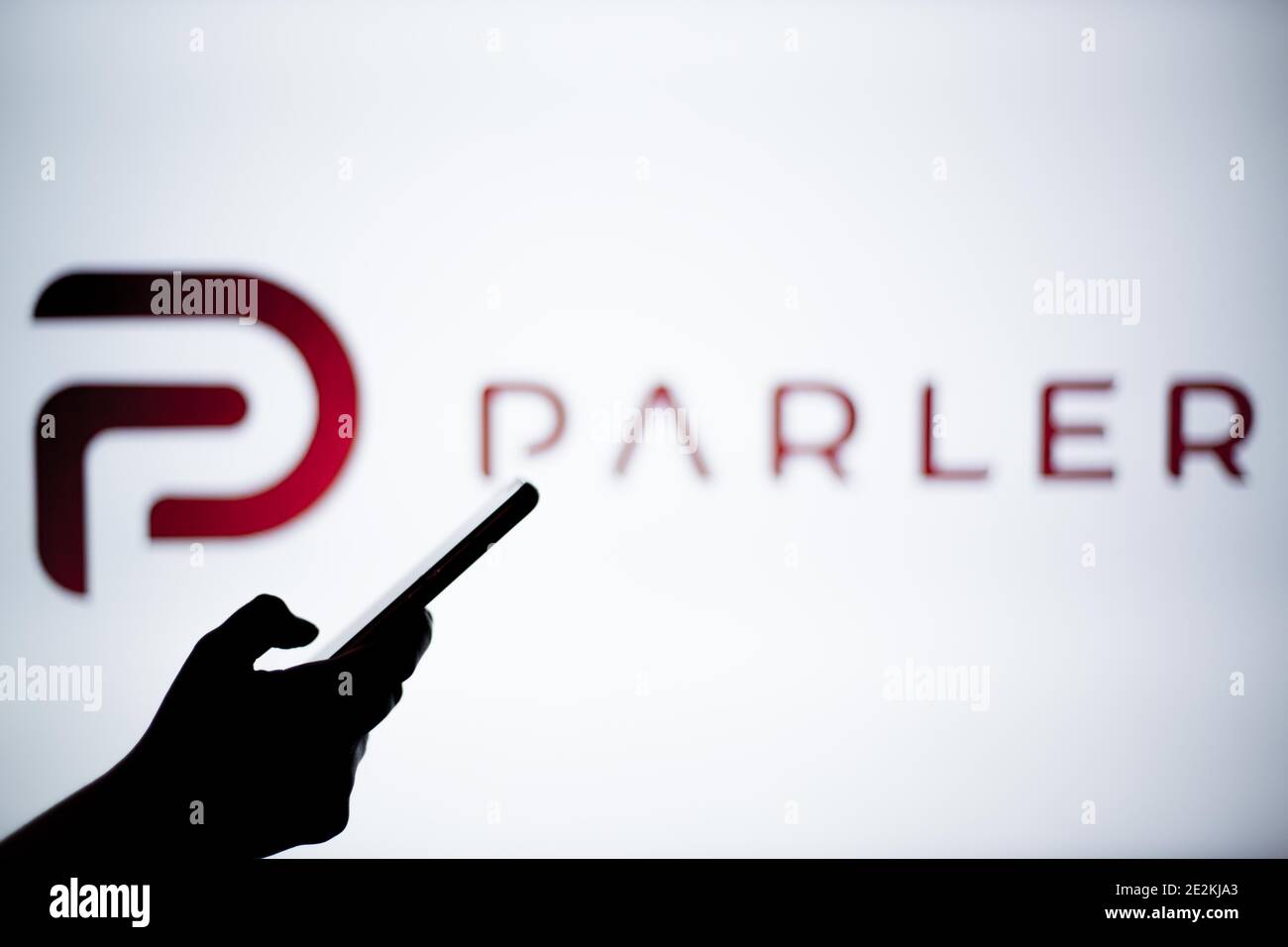 In this photo illustration a Parler logo is seen behind a smartphone ...