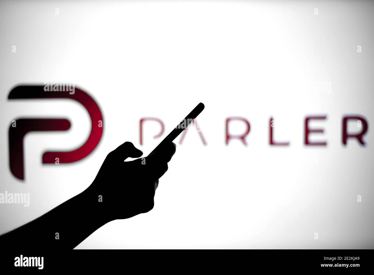 In this photo illustration a Parler logo is seen behind a smartphone ...