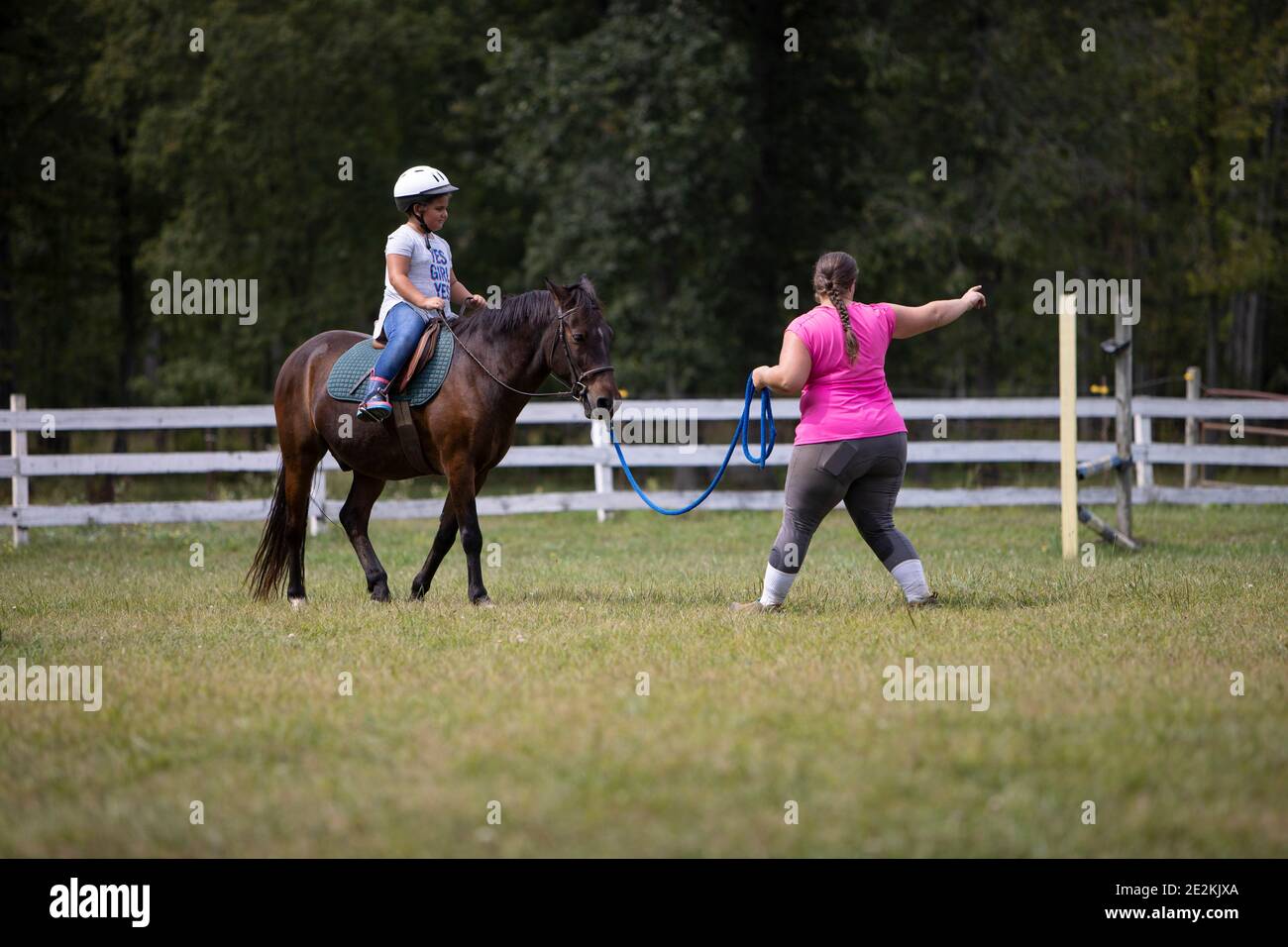 Woman giving a horseback riding lesson to a boy Stock Photo - Alamy