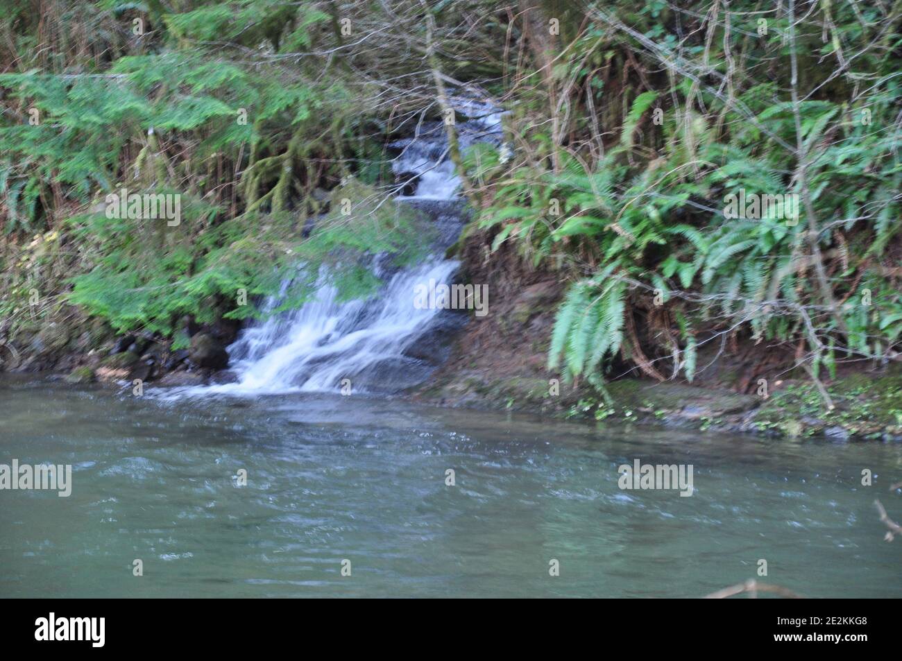 Small waterfall flowing into a river Stock Photo - Alamy