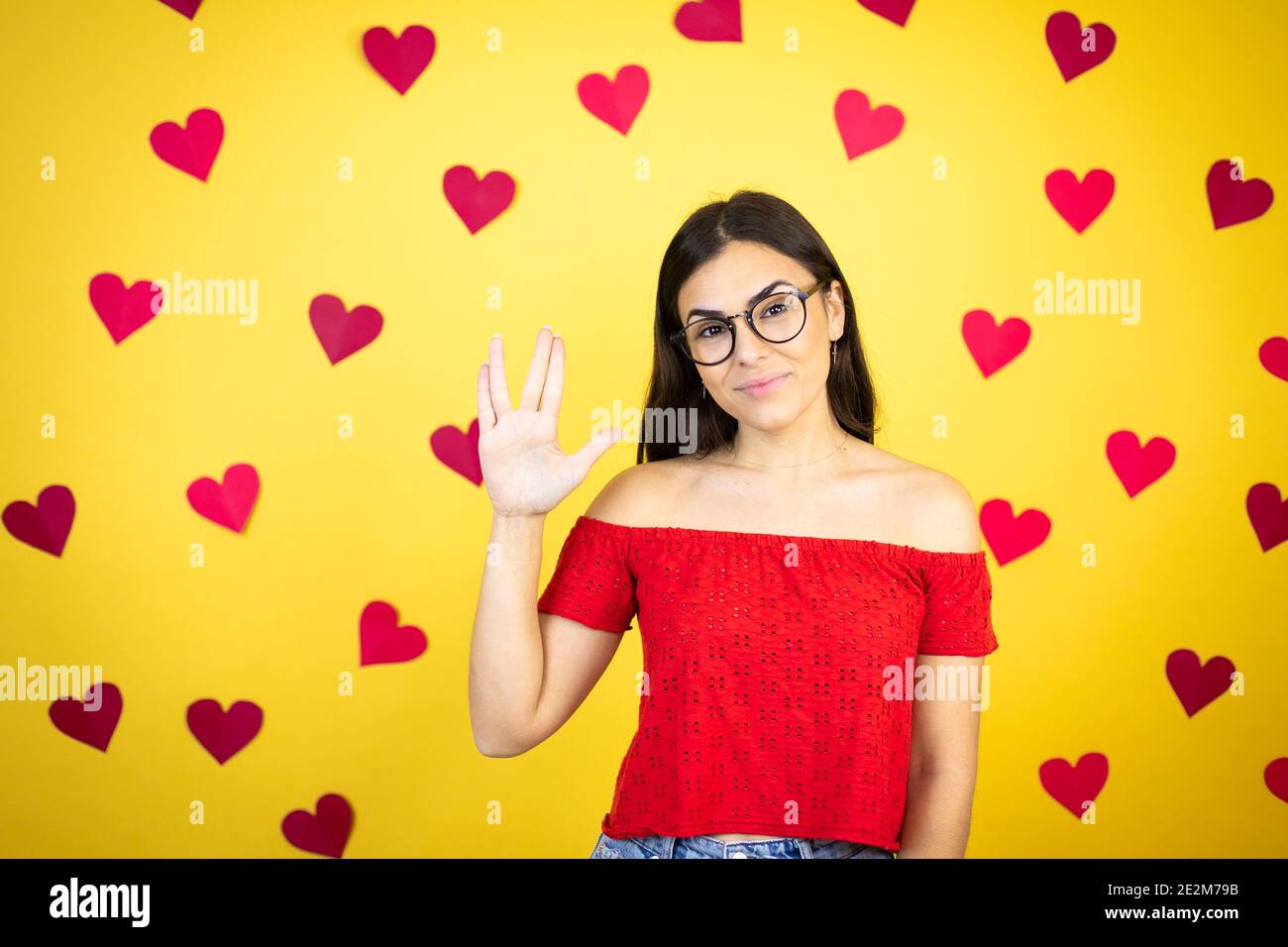 Young beautiful woman over yellow background with red hearts doing star ...