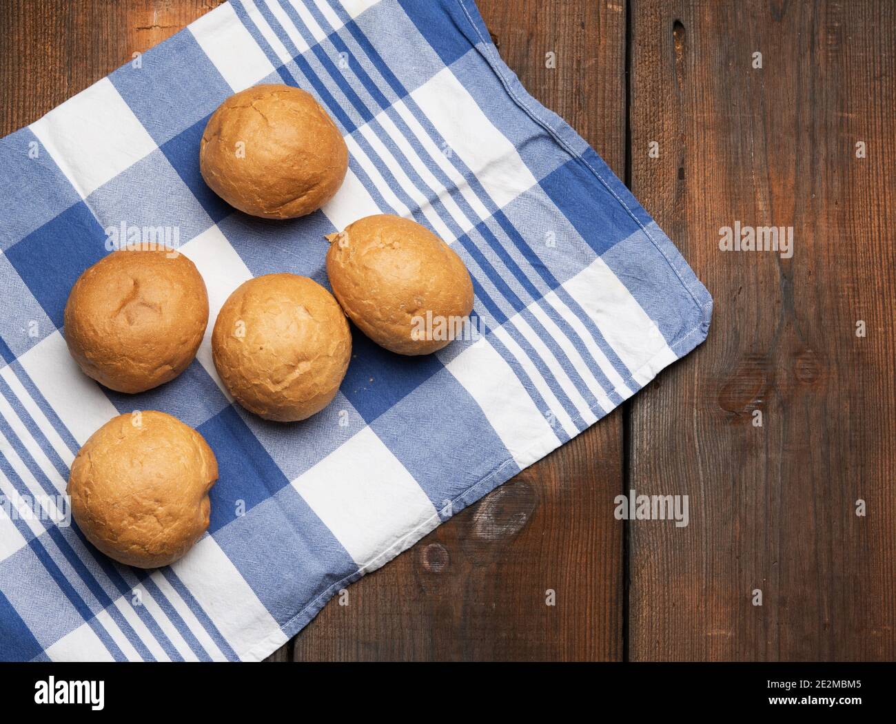 baked round small buns on a brown wooden table, top view Stock Photo ...