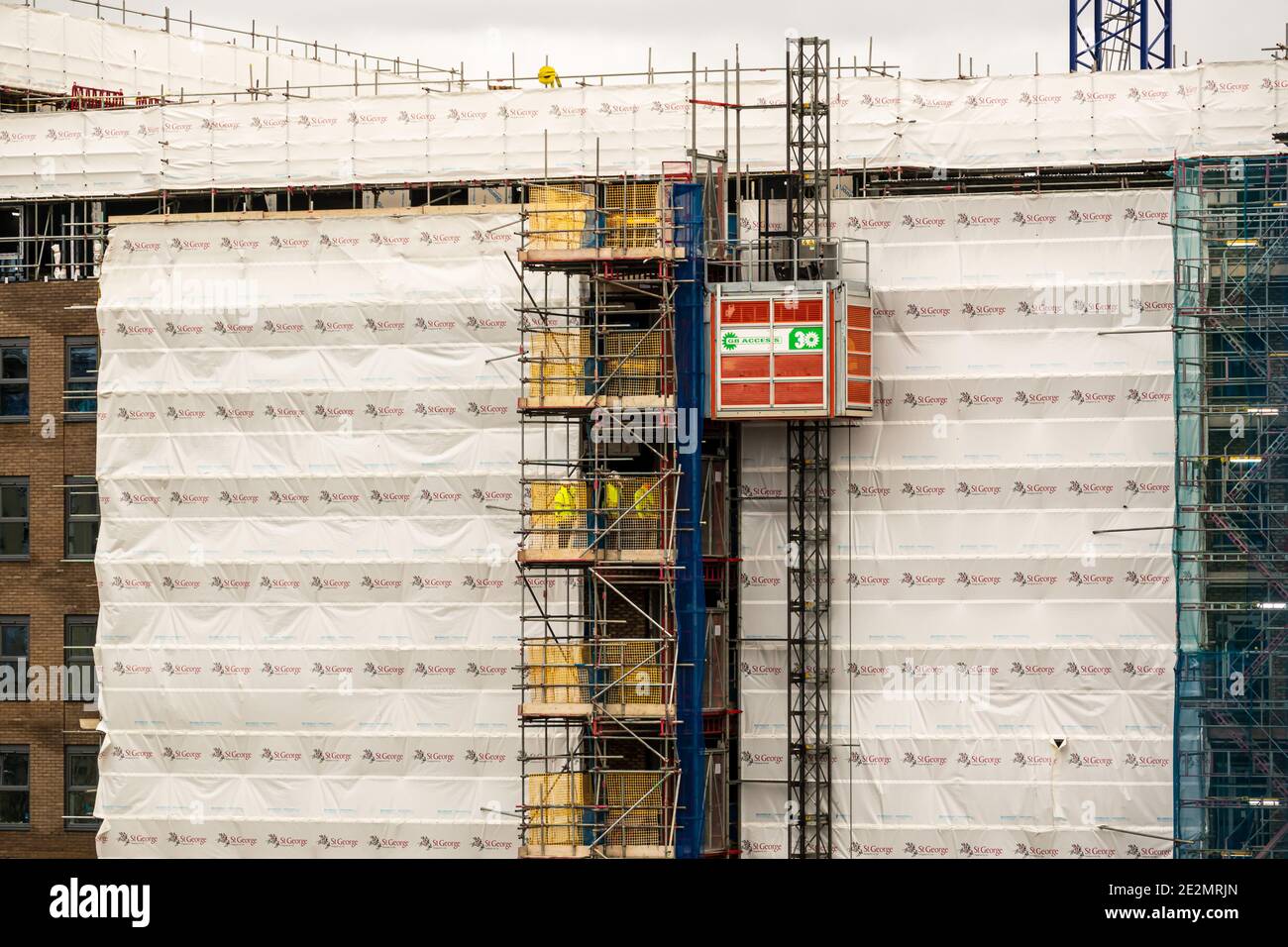 Builders and workers wait on scaffolding for the construction elevator ...