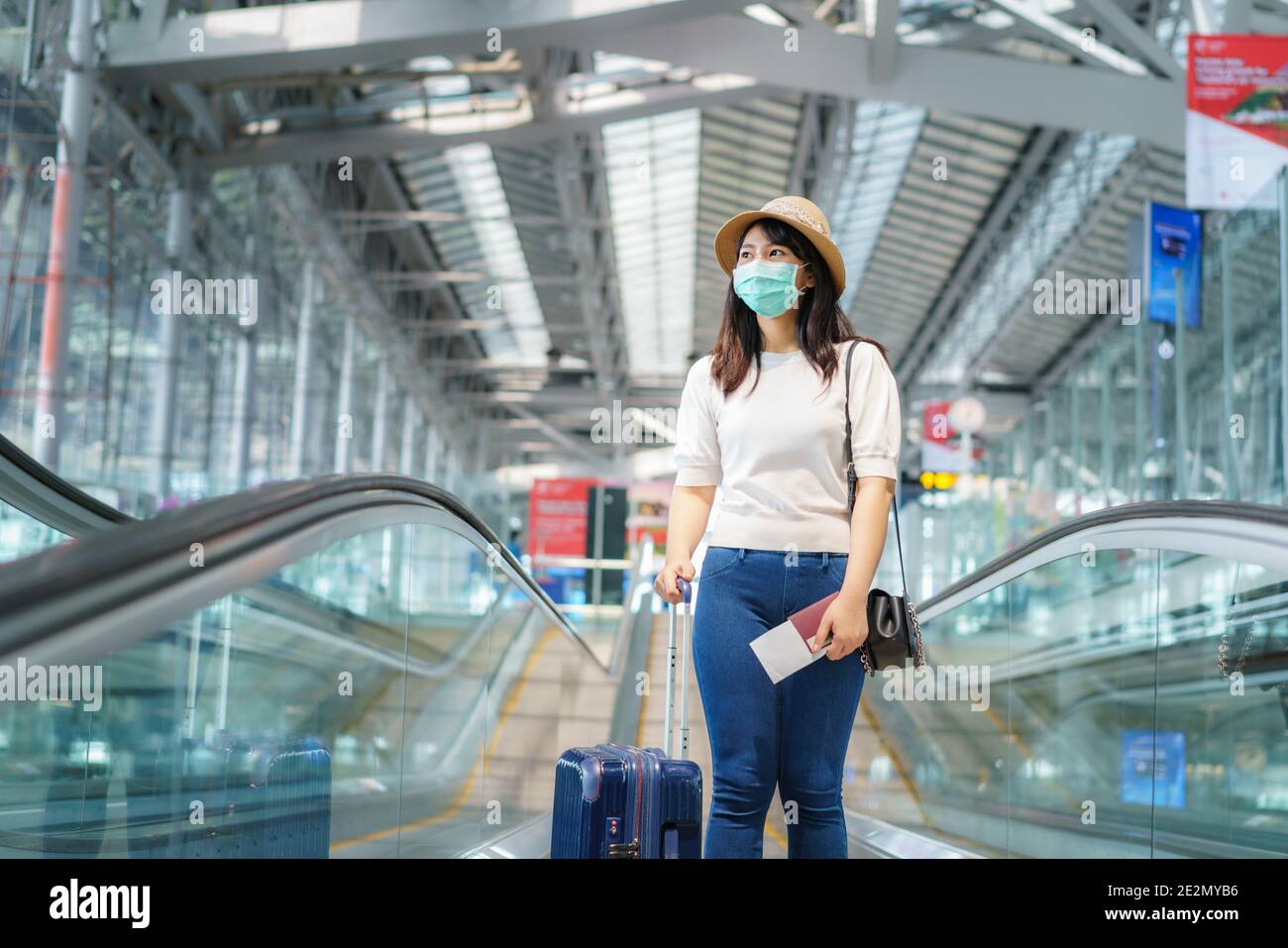 Asian traveler woman with luggage wearing face mask looking outside ...
