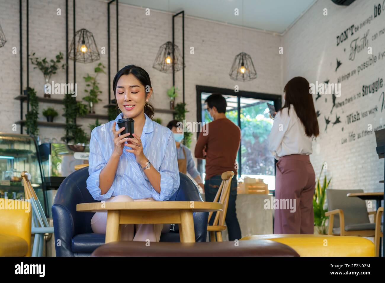 Asian woman sitting in cafe and feeling happy while she drink coffee ...