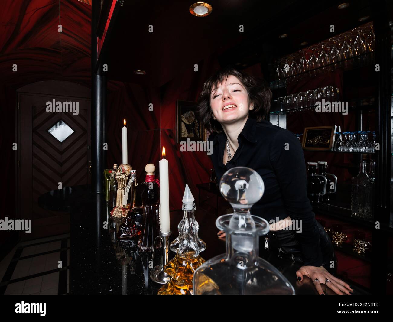 A young girl, dressed in a gothic style, poses in a posh alcoholic bar ...