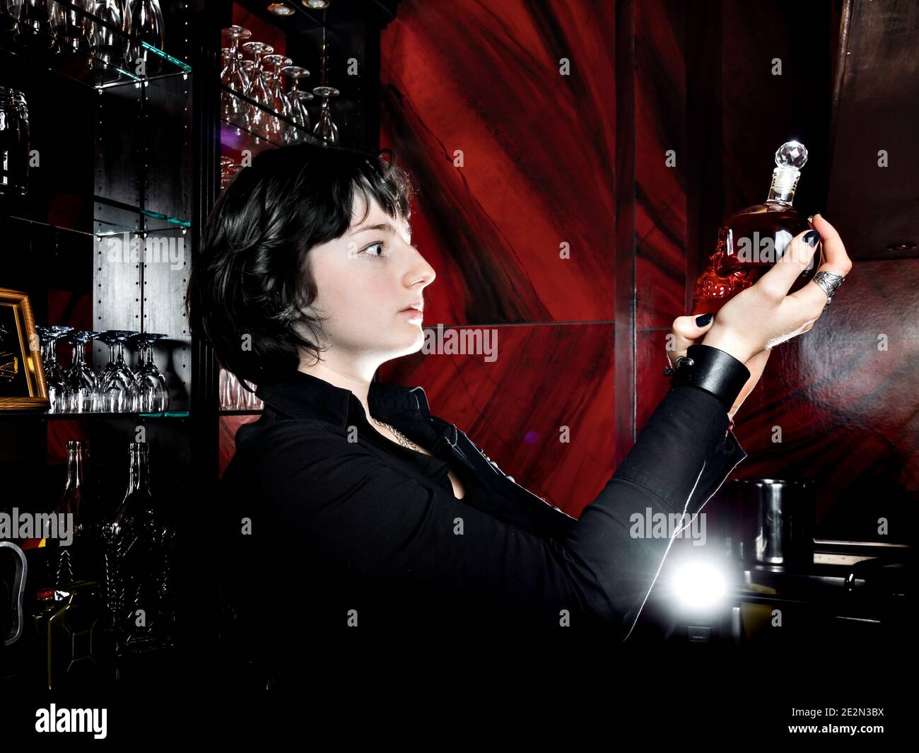 A young girl, dressed in a gothic style, poses in a posh alcoholic bar ...