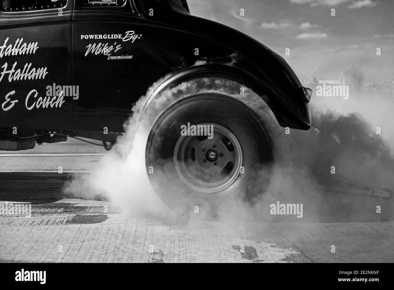 Drag racing car burns rubber off its tire with lots of smoke from ...