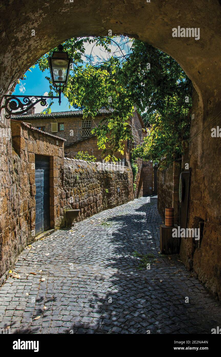 Narrow alley with sidewalk and stone walls. In the town of Orvieto, a ...