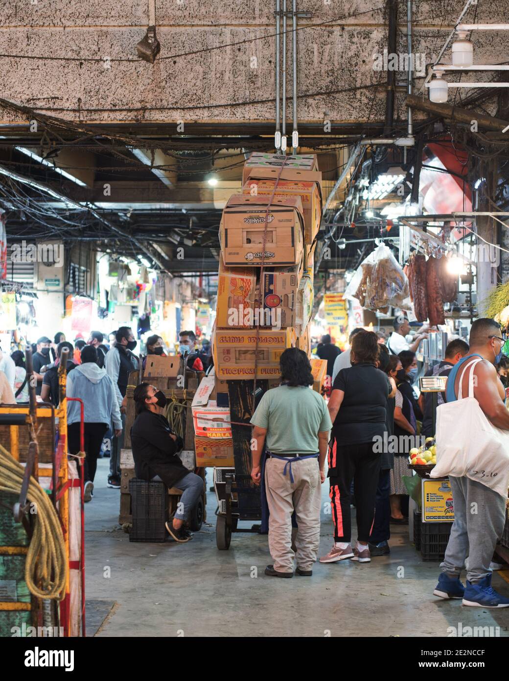 Crowd of people standing around stack of carton boxes in passage of ...
