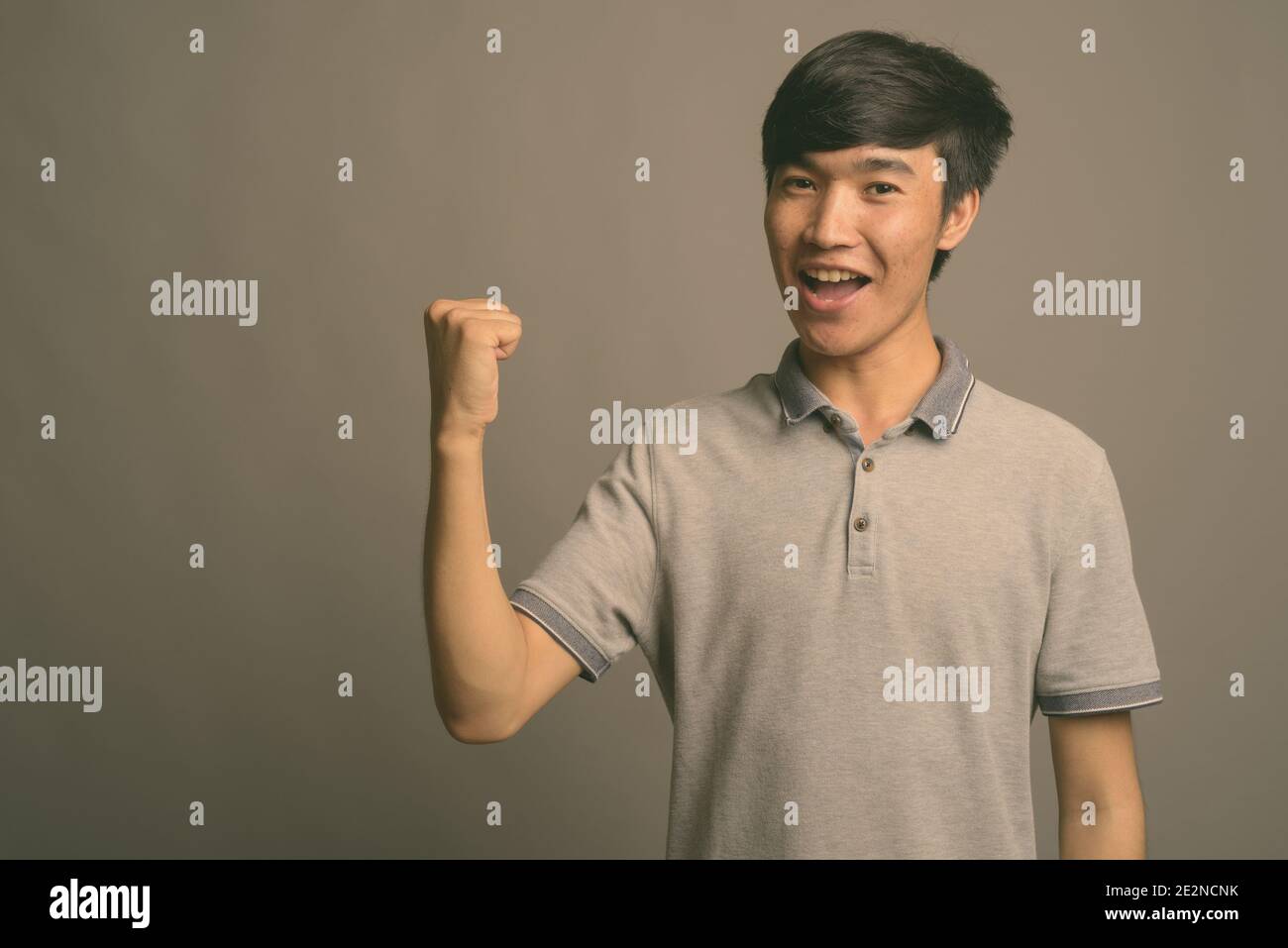 Young Asian man wearing gray polo shirt against gray background Stock ...