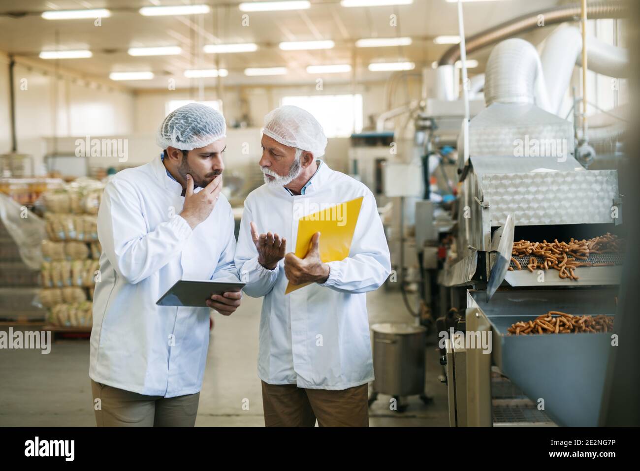 Workers talking about food quality. In hands chart and tablet Stock ...