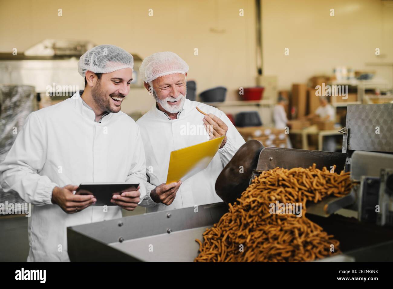 Proud father and son in sterile clothes standing in their food factory ...