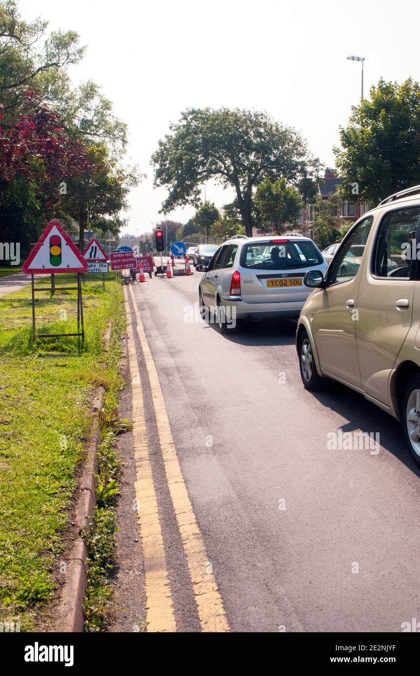 Cars waiting at road works with traffic warning & lane indicator signs ...