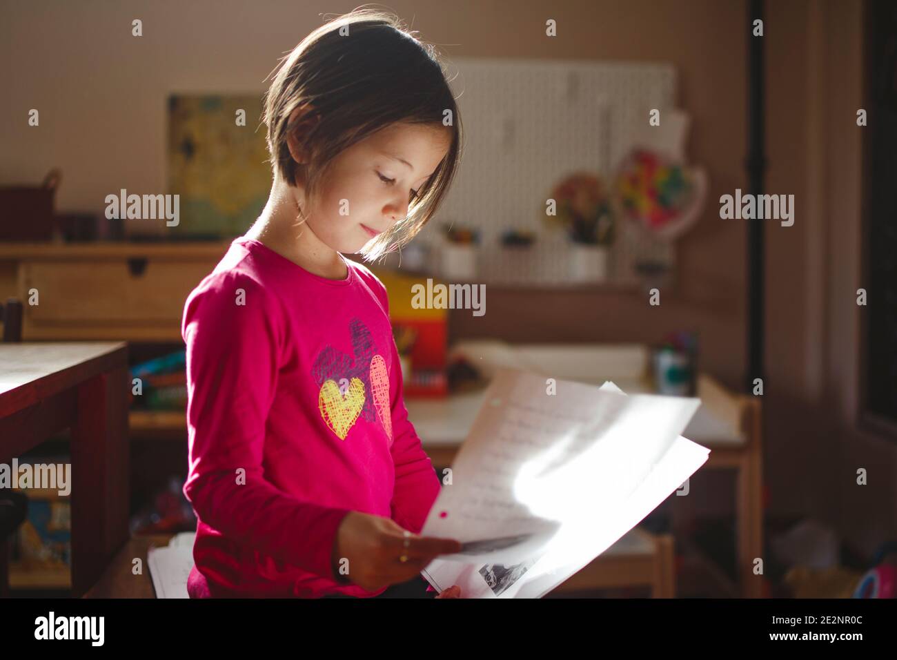 A little girl in beautiful light reads from sheets of paper Stock Photo ...