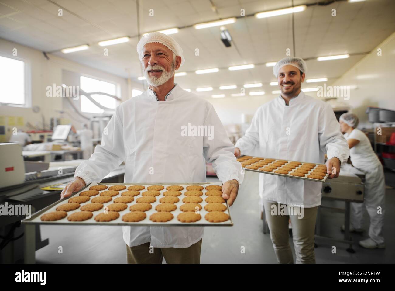 Picture of two male food factory employees in sterile clothes holding ...