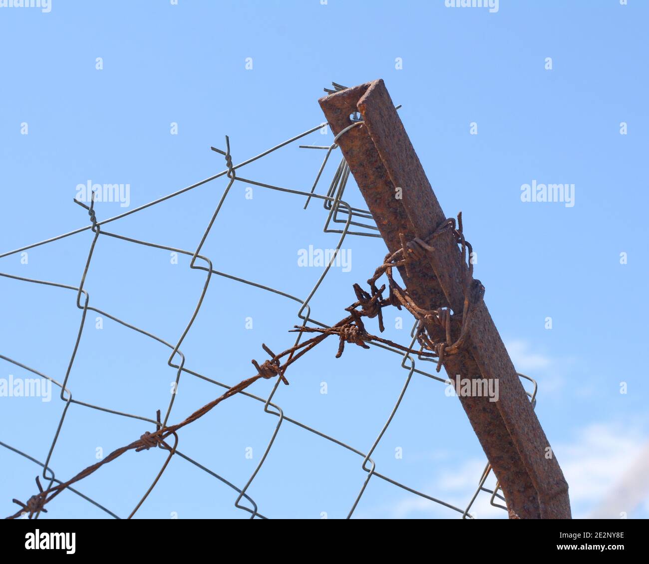 Rusty barbed wire and blue sky background Stock Photo - Alamy