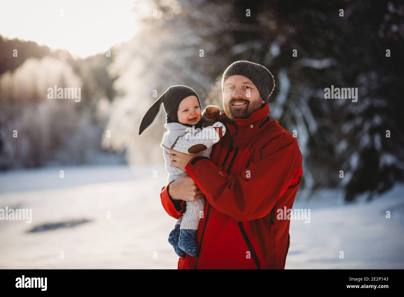 Father and baby smiling in winter wonderland full of snow in the woods ...