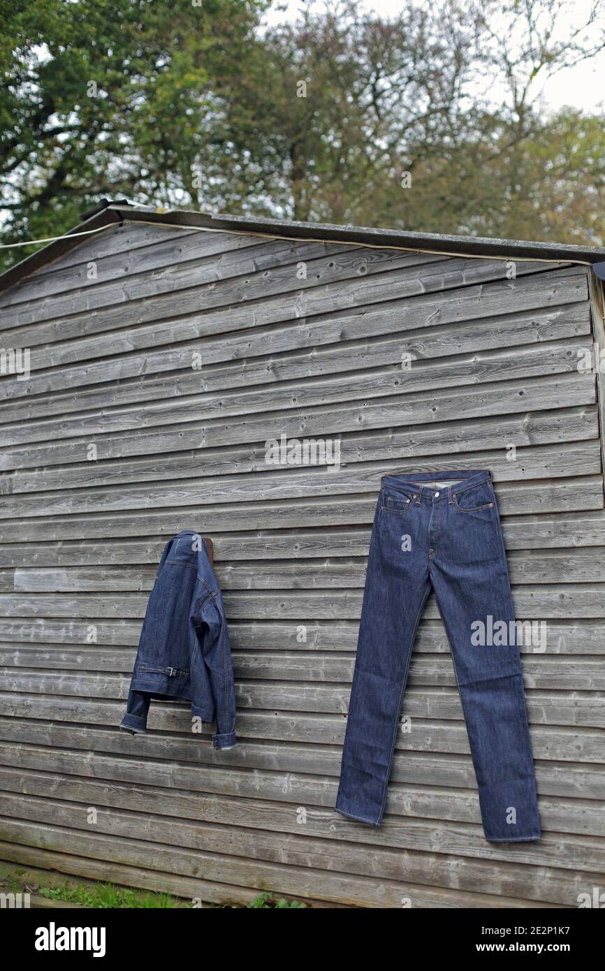 denim jeans and jacket nailed to wooden wall panels. An pair of cotton ...