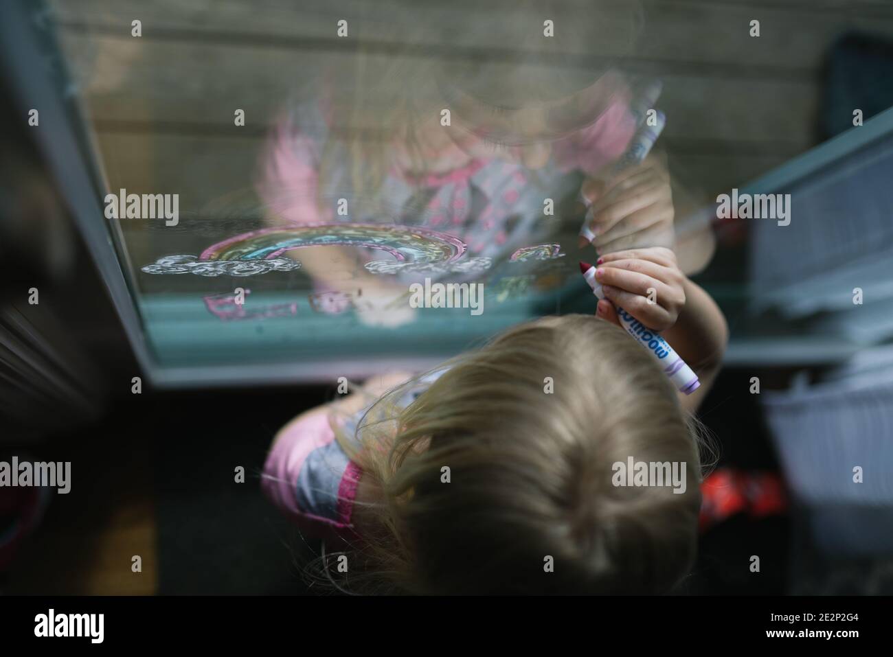 Above view of child drawing on window with markers Stock Photo - Alamy