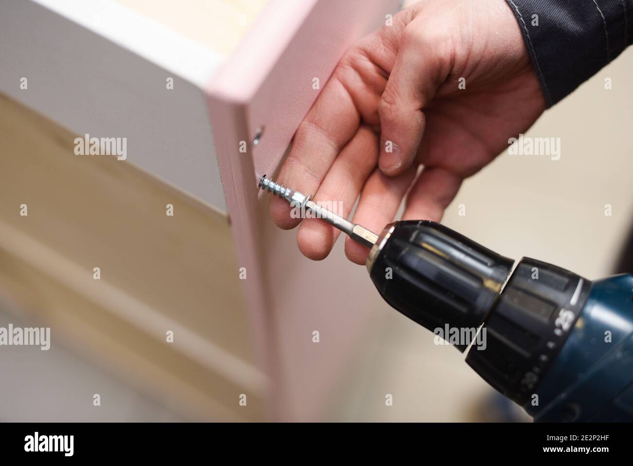 Carpenter working on cabinet furniture. Tightening screws with ...
