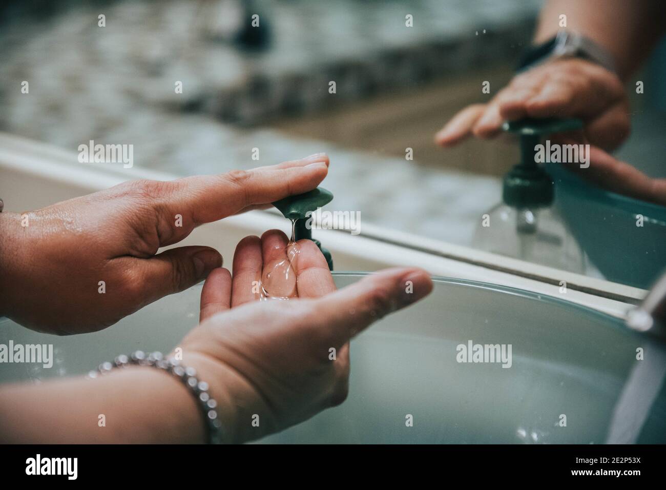 Shot of the hands of a person pushing button of liquid soap bottle to ...