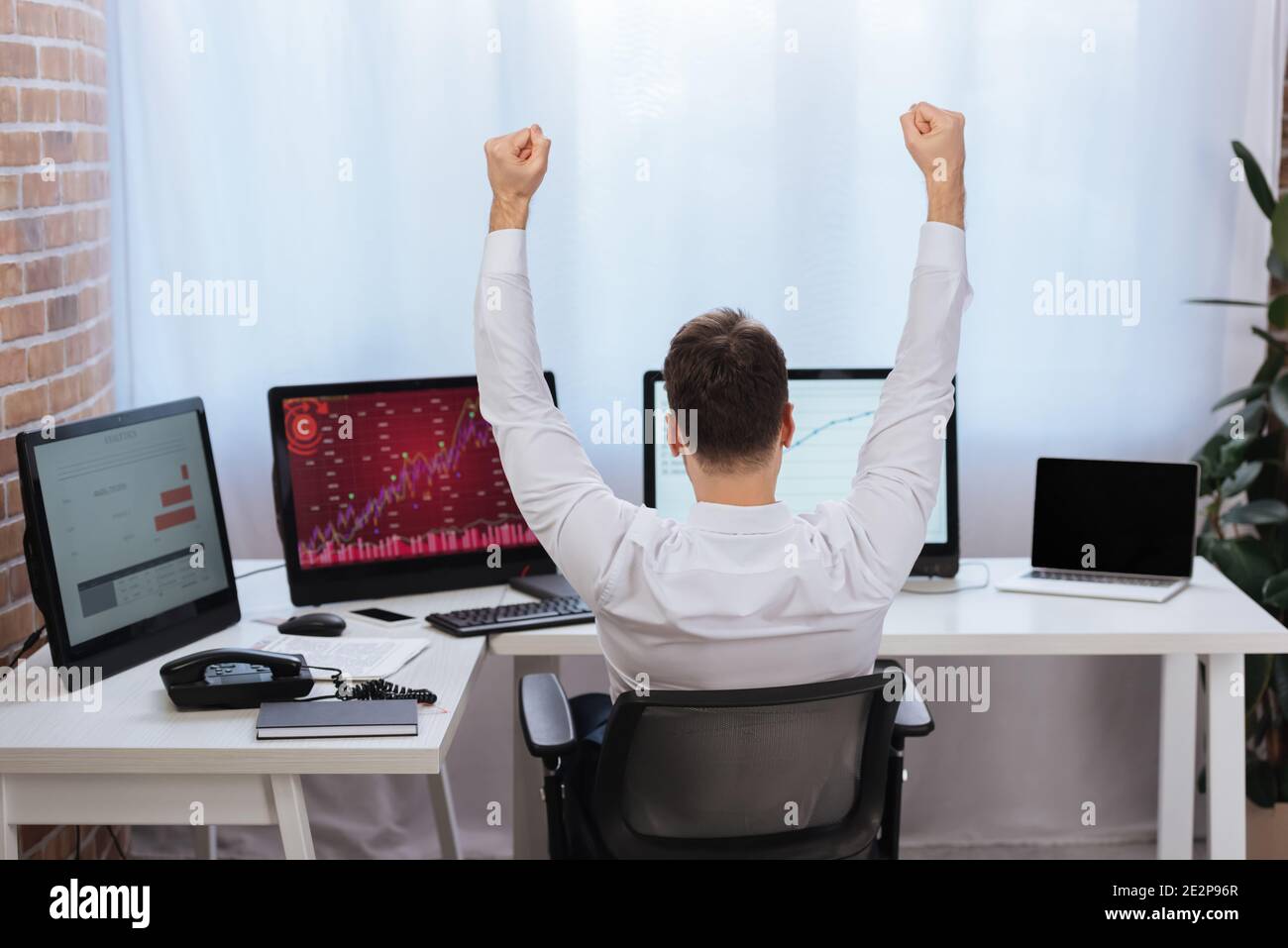 Back view of forex businessman showing yeah gesture near computers with ...