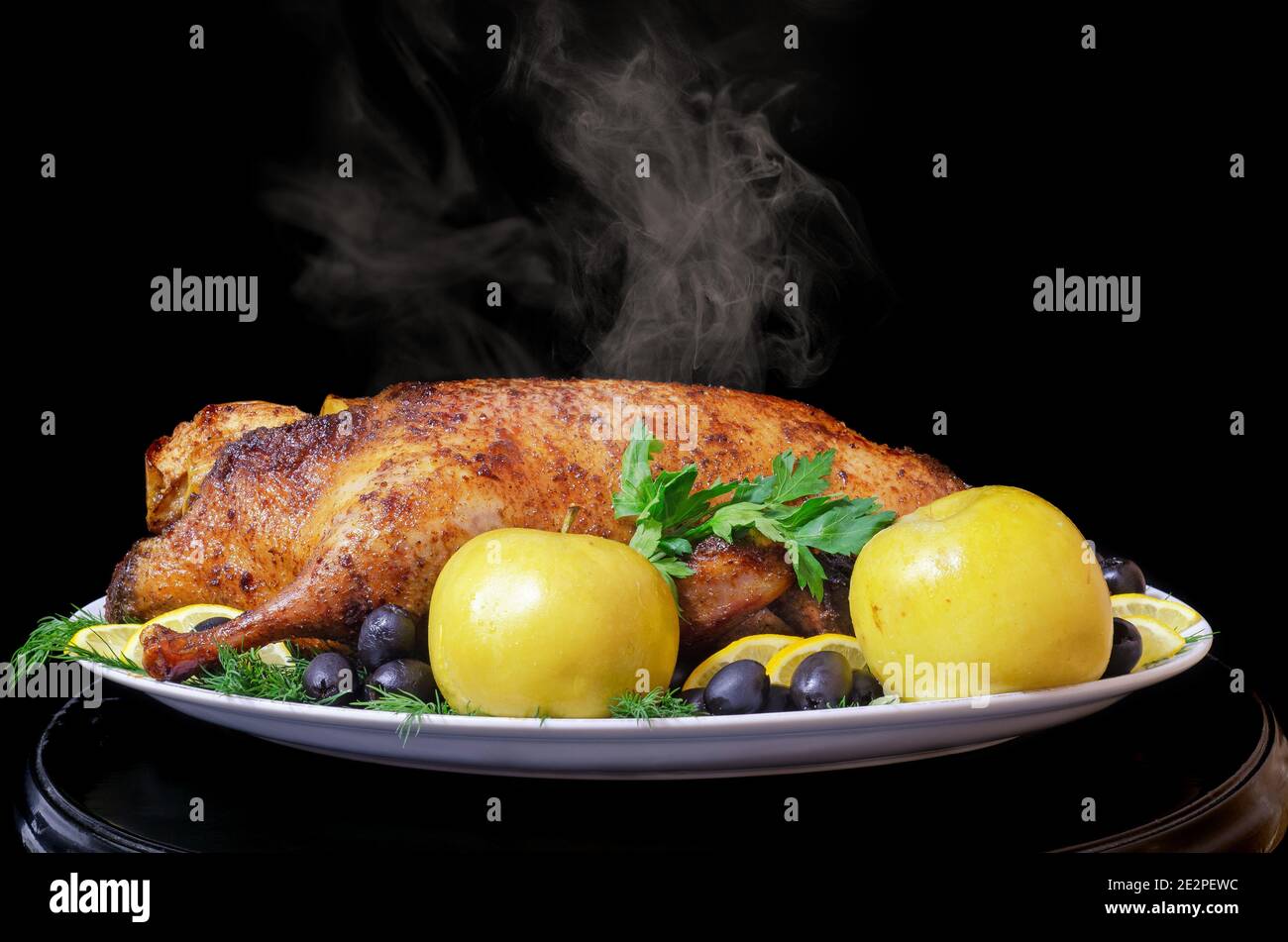 Roast duck with apples, lemon, olives and herbs on a black background ...