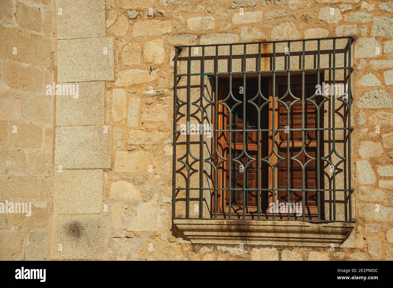 Wooden window with wrought iron grid on the stone facade of gothic ...