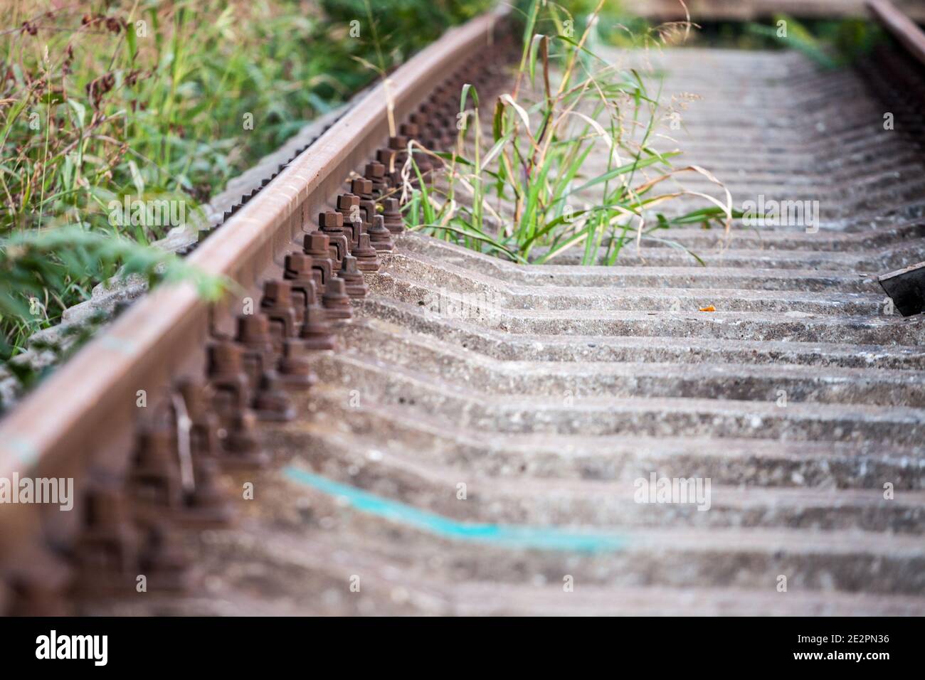Concrete sleeper on an old railroad track with weeds and grass on an ...