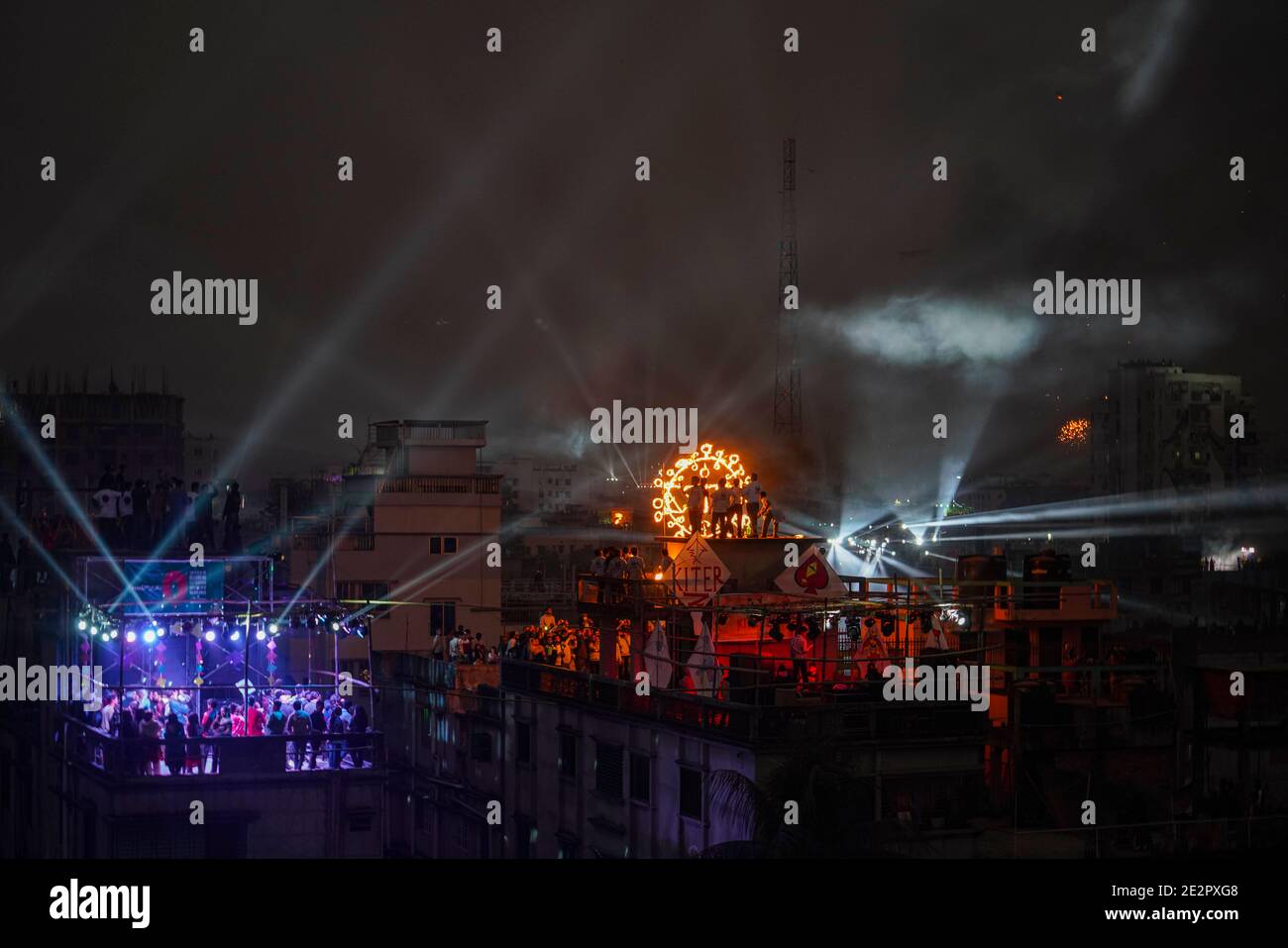 Bangladeshi people set up party lights and perform dance on a rooftop ...