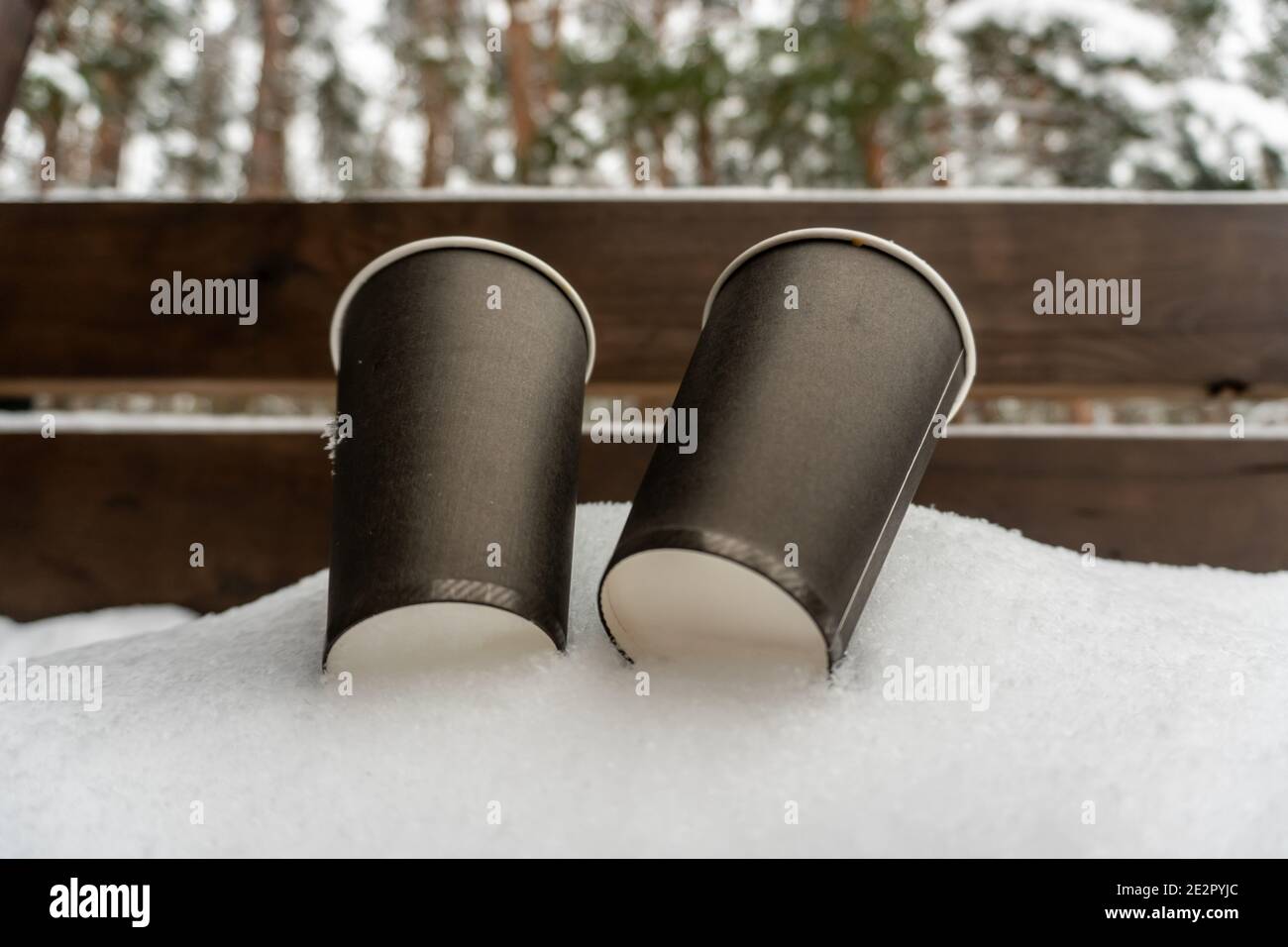 Two paper cups with coffee on a snow bench kissing each other, winter ...