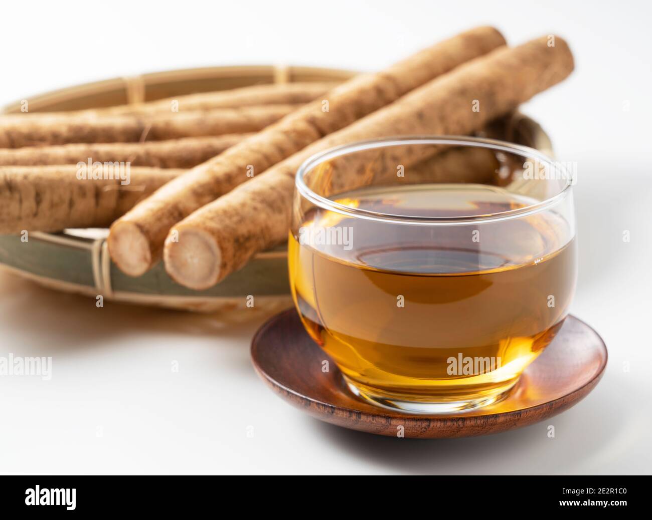 Burdock tea on a white background. A raw burdock behind it Stock Photo ...