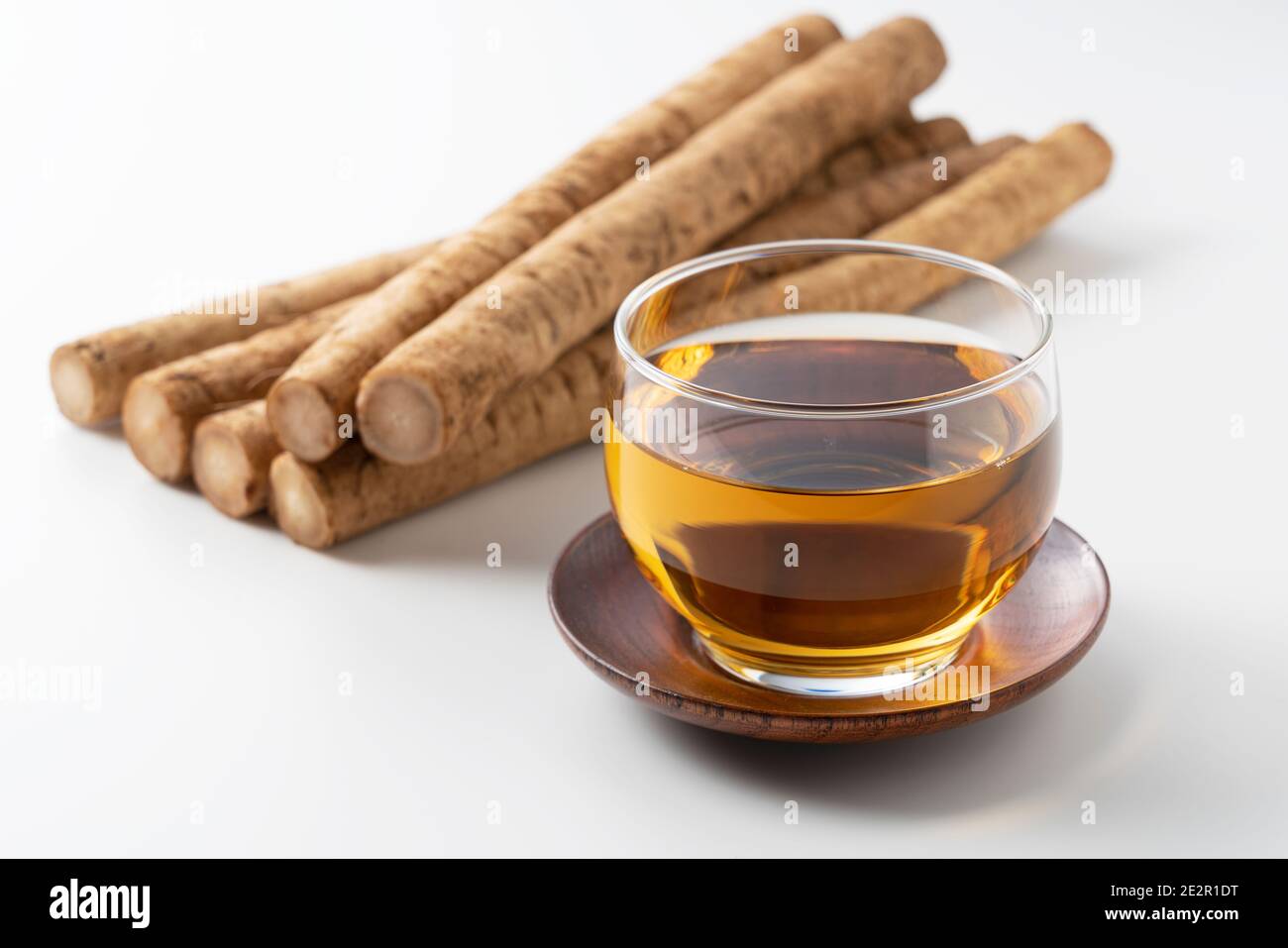Burdock tea on a white background. A raw burdock behind it Stock Photo ...