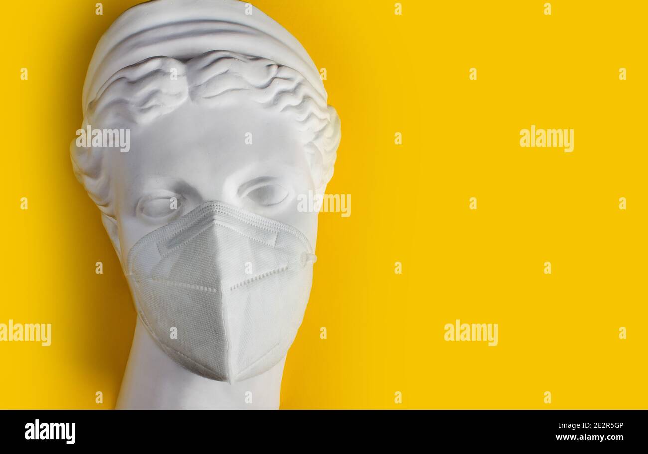 Photo of a female greek gypsum statue face with medical protective mask ...