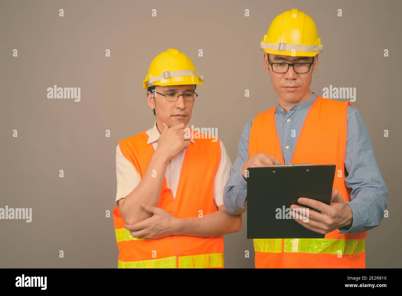Two young Asian men construction worker together against gray ...