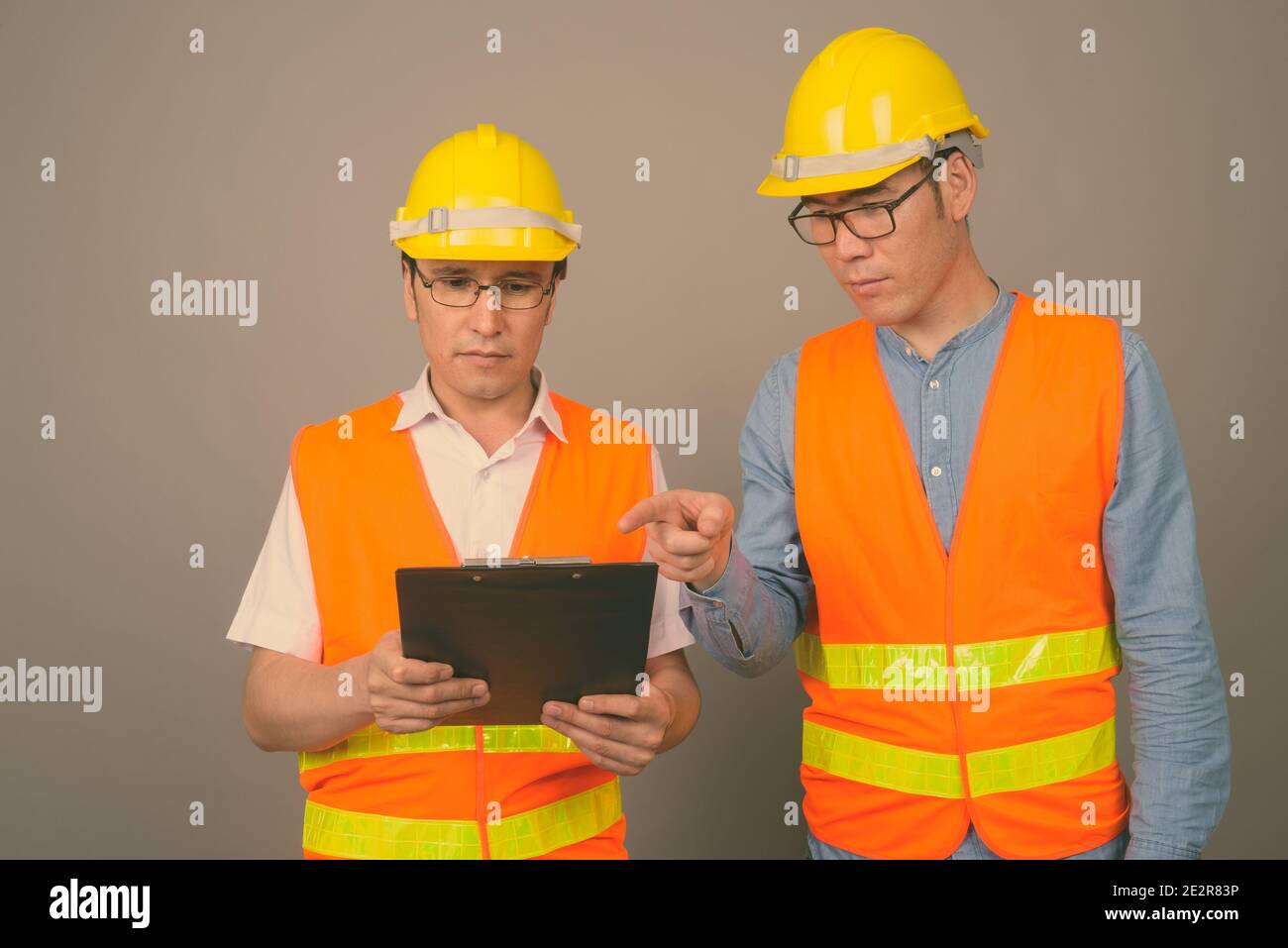 Two young Asian men construction worker together against gray ...
