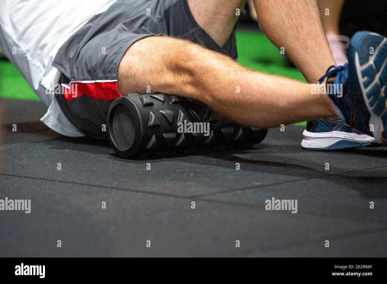 Adult male using a foam roller in the gym Stock Photo - Alamy