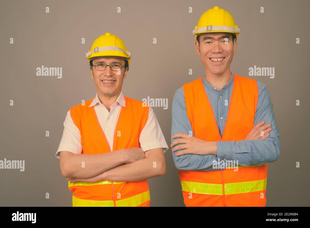 Two young Asian men construction worker together against gray ...