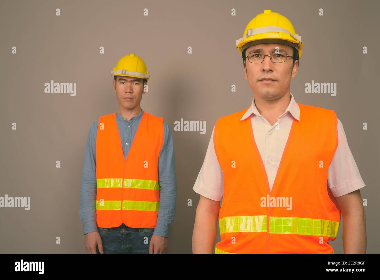 Two young Asian men construction worker together against gray ...