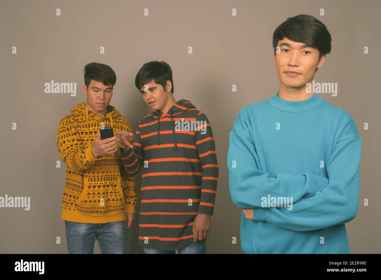 Three young Asian friends together against gray background Stock Photo ...