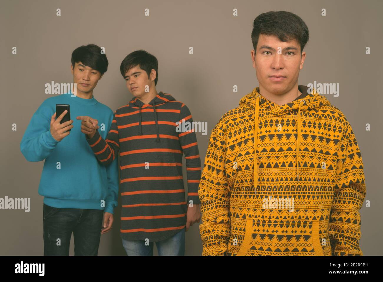 Three young Asian friends together against gray background Stock Photo ...