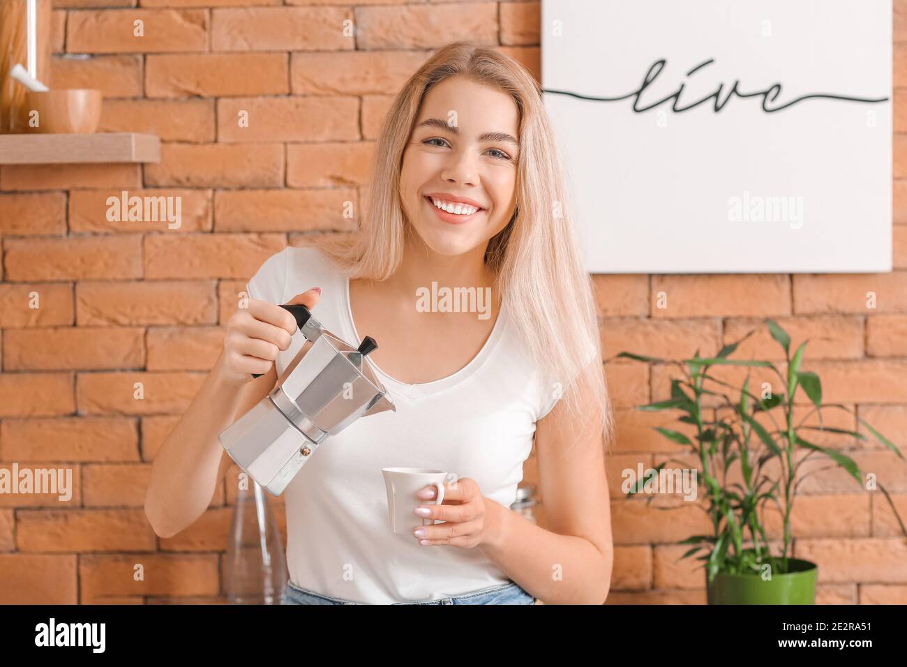 Beautiful young woman drinking hot coffee in kitchen Stock Photo - Alamy