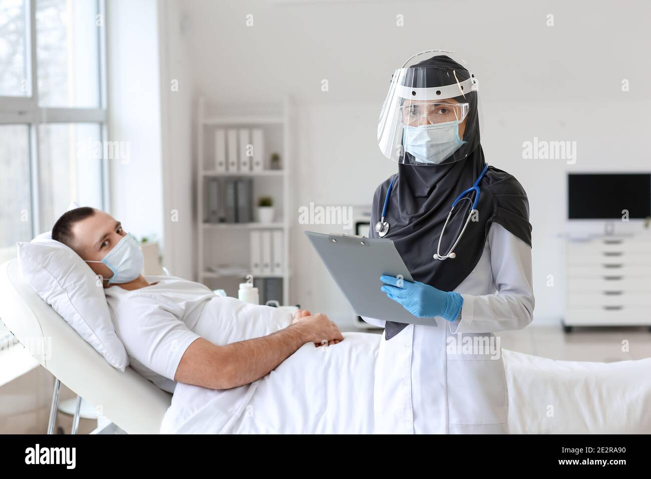 Female Muslim doctor visiting male patient in clinic Stock Photo - Alamy