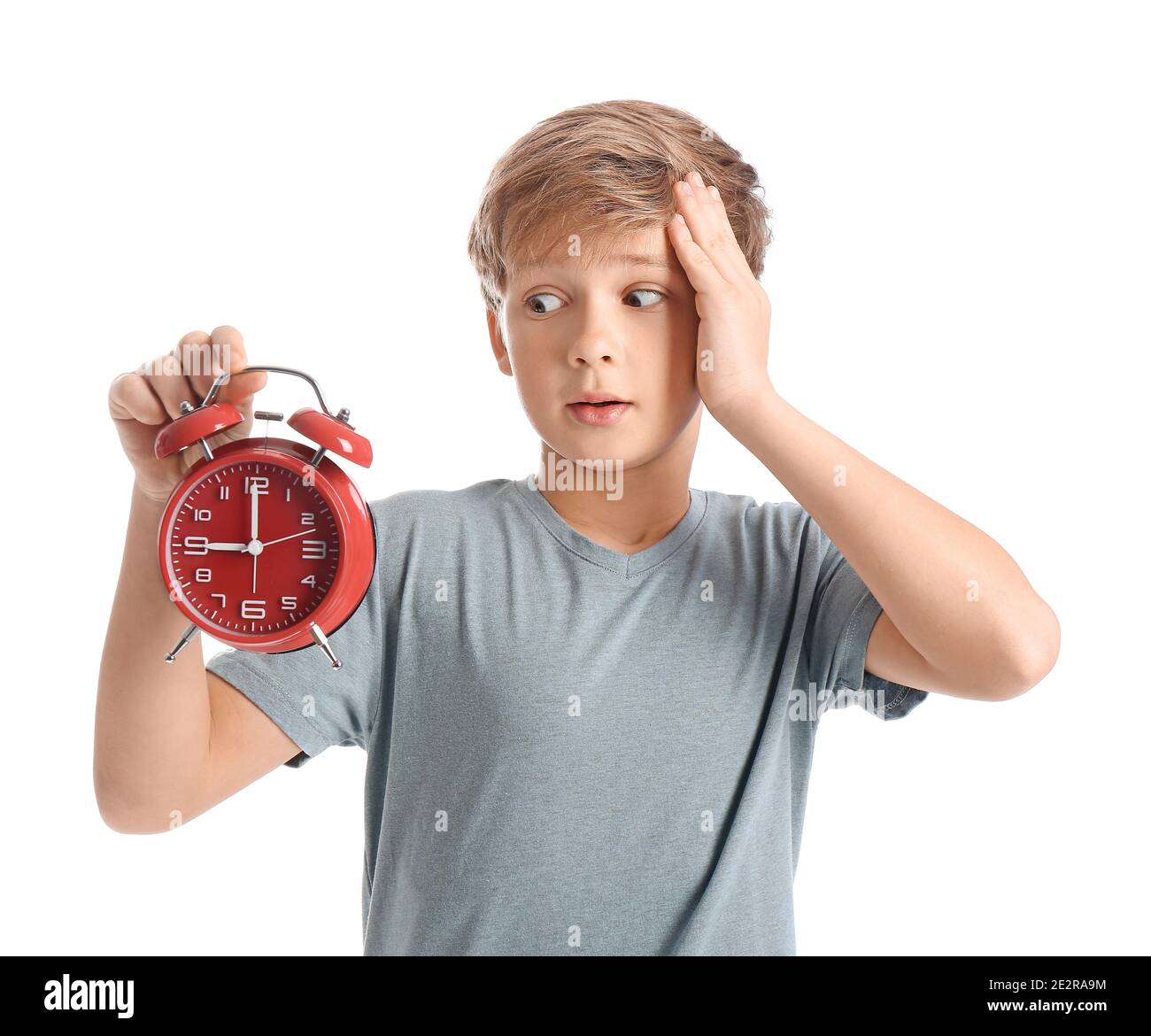 Emotional little boy with alarm clock on white background Stock Photo ...