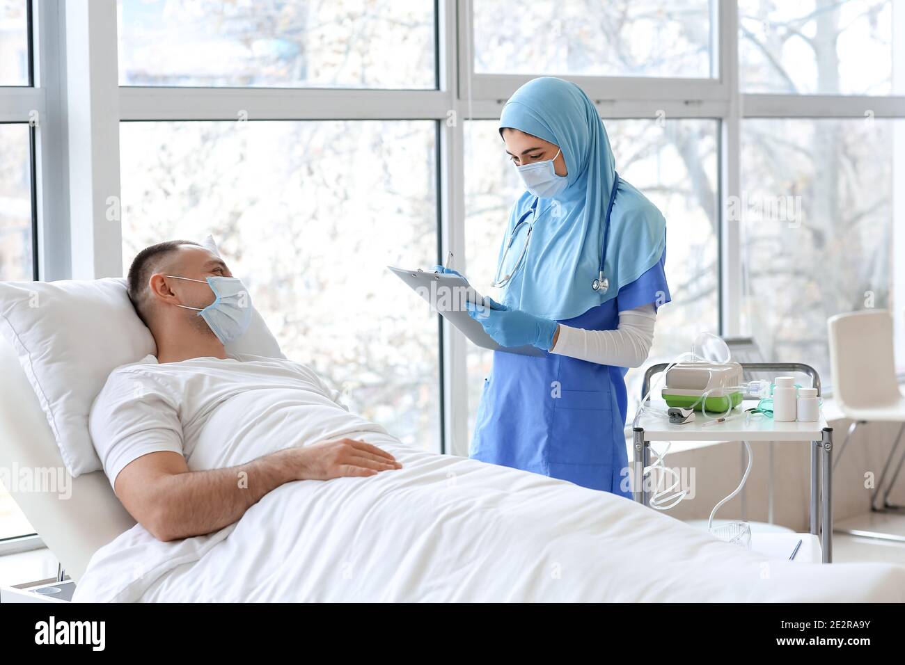 Female Muslim doctor visiting male patient in clinic Stock Photo - Alamy